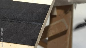 Roofer cutting roll roofing felt or bitumen during waterproofing works. Roofing repair.Worker Install and Repair Asphalt Shingles for the Rooftop Outdoor.