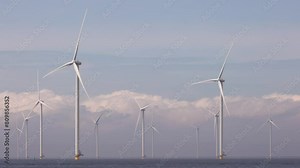 Wind farm of wind mills, generators, wind turbines, off shore in a sea or lake IJsselmeer in the Netherlands. Multiple tall windmills and rotor blades generating green sustainable energy, electricity