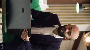 Vertical Video People in telework session online undertaking business meetings while seated at hotel entrance lounge. On a video conference, supervisory team interacts with front desk and remote staff