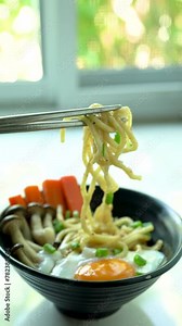 Delicious soba noodles on chopsticks Noodles with sliced scallions, eggs and mushrooms in a simple, homemade black bowl. Asian menu. Food, Vertical video