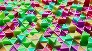 Looping animation of a group of multicolored plastic geometric shapes.