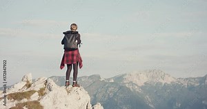 Young woman on a hike climb on peak or summit top lift extend arms look at the view after success in the morning hiking in fall or autumn