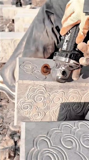 Intricate cloud-pattern stone carving created using a handheld rotary grinder tool