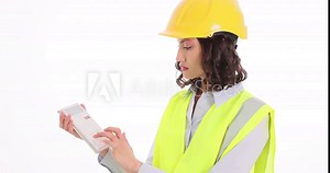 Woman architect in helmet uses engineering calculator on white. Focused female in uniform creates calculations for construction site project slow motion