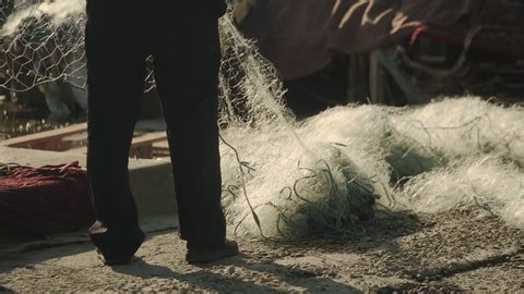 clip-4008503391-fishermen-collecting-fishing-nets-harbor-after-catch