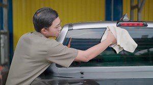 A man cleaning the window of a car