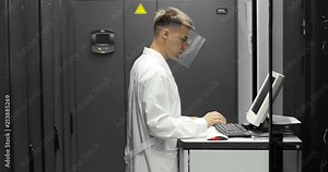IT Technician Works on a compuiter in Big Data Center full of Rack Servers. He Runs Diagnostics and Maintenance Stets up System.