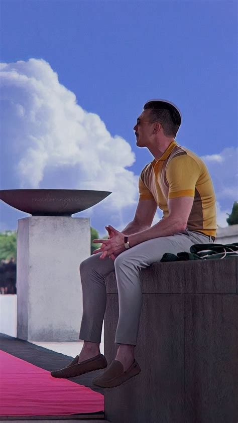 A Man Sitting On Top Of A Cement Wall Next To A Pink Carpeted Floor