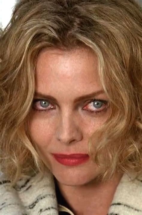 A Woman With Blonde Hair And Blue Eyes Wearing A White Sweater Is