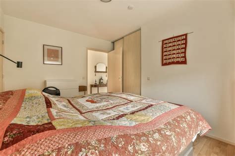 Uma Cama Colchas Em Um Quarto Paredes Brancas E Piso De Madeira