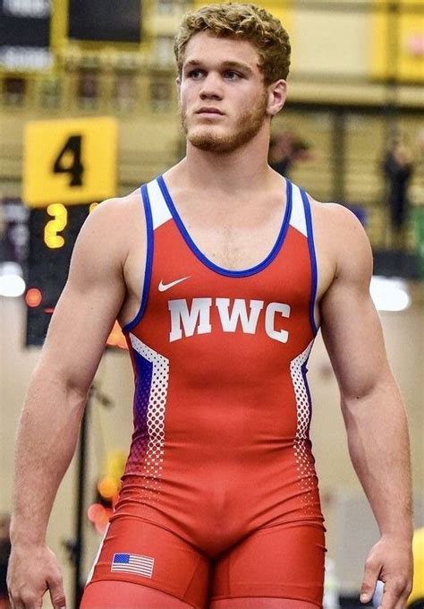 A Man In Red And Blue Wrestling Suit With His Hands On His Hips Looking At The Camera