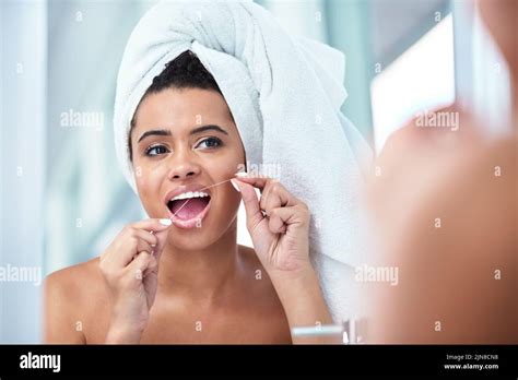 Flossing For Healthier Teeth A Woman Flossing Her Teeth While Wearing A Towel Wrapped Around