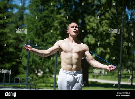 Athletic Muscular Man Jumping With A Rope Workout Outdoors At Sunny