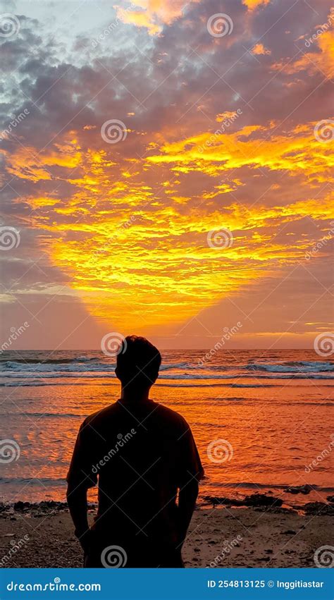 Silueta De Un Hombre Parado En La Playa Mirando A La Puesta De Sol Que