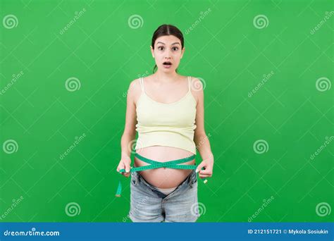 Cropped Image Of Expecting Mother In Unzipped Jeans Measuring Her Pregnant Belly With A Tape