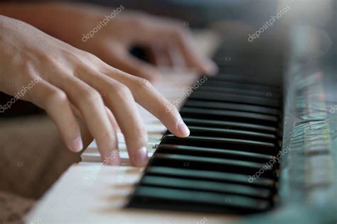 Tocando el teclado del piano de cerca Manos recortadas de niño tocando