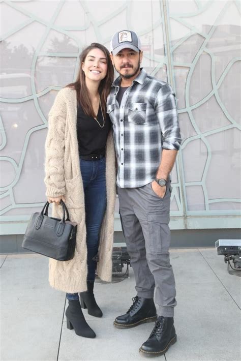A Man And Woman Standing Next To Each Other In Front Of A Wall With