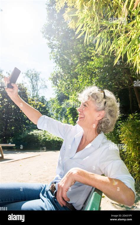 Side Portrait Happy Middle Age Woman Sitting On Park Bench Taking