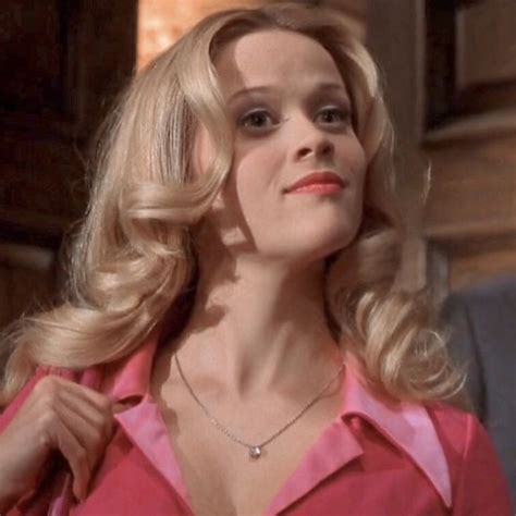 A Woman With Blonde Hair Wearing A Pink Shirt And Diamond Necklace In A