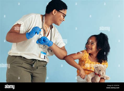 Doctor Giving Elbow Bump To Girl After Vaccination In Clinic Doctor And Girl Patient Greeting