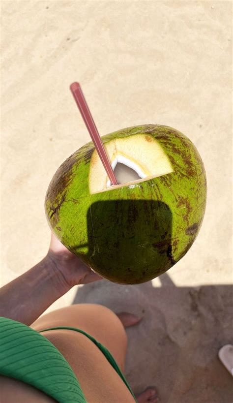 A Person Holding A Green Coconut Drink In Their Hand