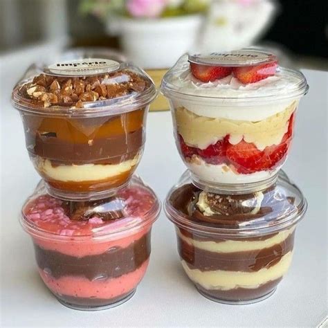 Four Desserts In Plastic Containers Sitting On A Table