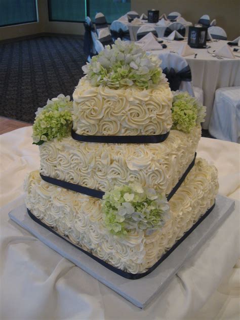 Three Tiered Wedding Cake Sitting On Top Of A Table Covered In White Linens