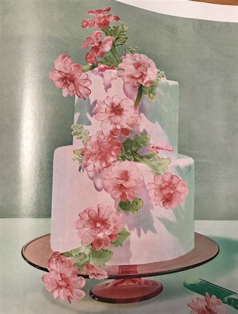 A Three Tiered Cake With Pink Flowers On The Top And Green Leaves On