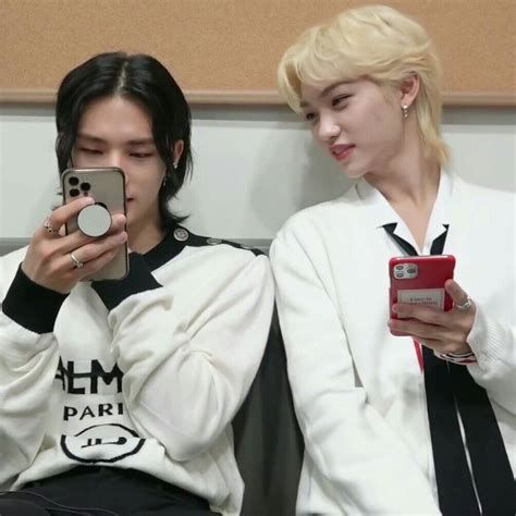 Two People Sitting Next To Each Other While Looking At Their Cell