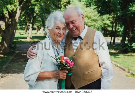 Old Couple Is Walking In The Green Park Grandmother And Grandfather At Their Golden Wedding