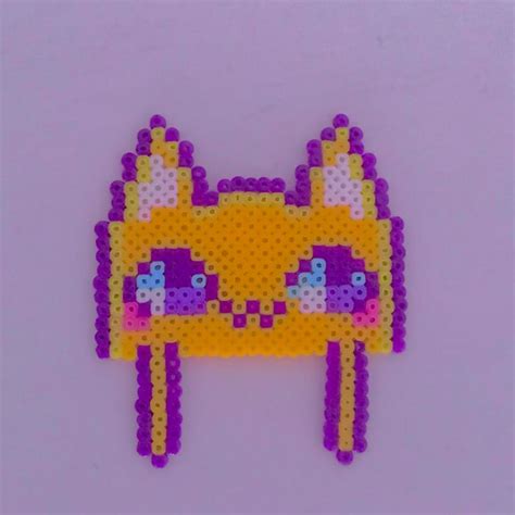 A Yellow And Purple Beaded Brooch Sitting On Top Of A White Table Next