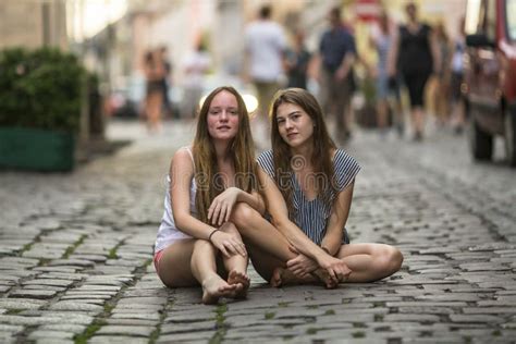 Deux Jeunes Filles S Asseyant Ensemble Sur Le Trottoir En Pierre Image