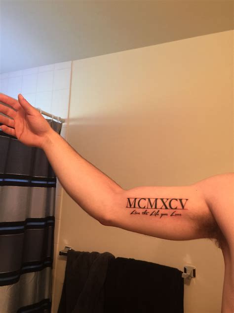 A Man S Arm With The Word Mcmxcy Tattooed On It In Black Ink