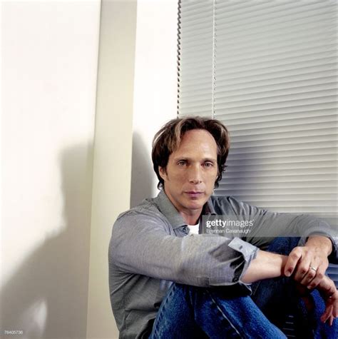 A Man Sitting In Front Of A Window With His Hands On His Knees Stock Photo
