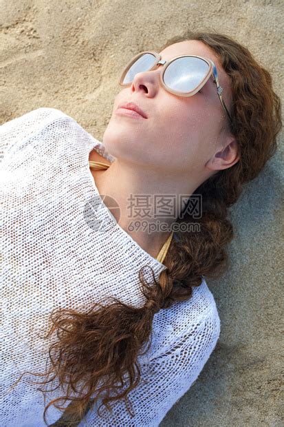 一个有魅力的年轻女子躺在金色沙滩上放松和戴着墨镜保护她的眼睛的头顶肖像视图旅行和健康的生高清图片下载 正版图片503356518 摄图网