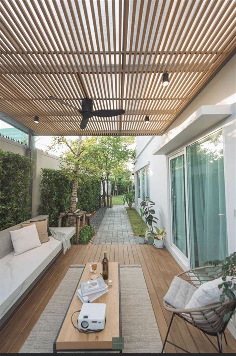 An Outdoor Living Area With Couches Tables And Plants On The Side Of It
