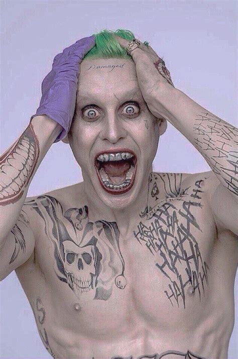 A Man With Green Hair And Tattoos Holding His Hands Up To His Head