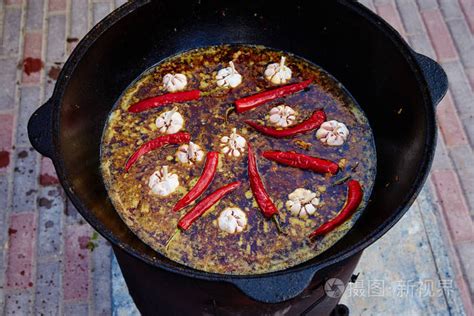 国家乌兹别克菜抓饭糊抓饭饭在大锅里的肉烹饪过程中一口药锅在火上准备阶段倒出水稻 添加水域 红辣椒和整个大蒜照片 正版商用图片