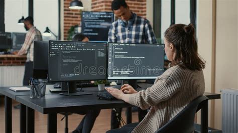focused software developer writing code looking at multiple computer screens stock image image