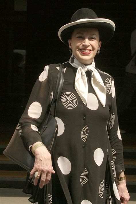 Geneviève de Fontenay en chapeau bicolore et chemise noire imprimée de