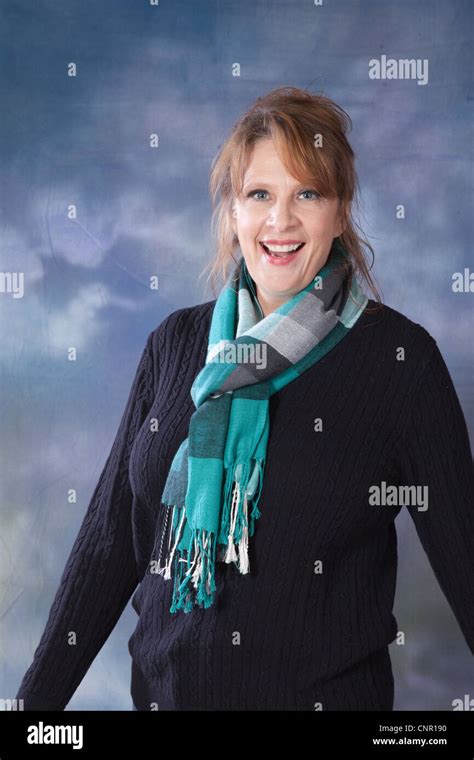 Lovely Mature Caucasian Woman In A Sweater And Scarf Smiling At The Camera With Happy