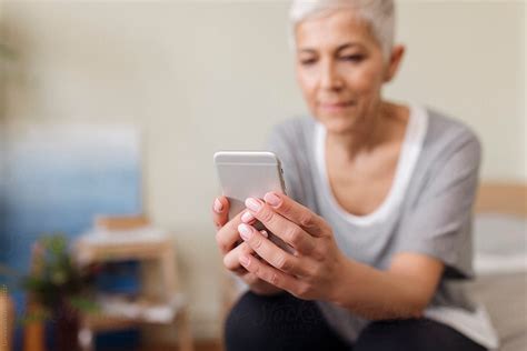 Woman Using A Mobile Phone At Home By Stocksy Contributor Lumina