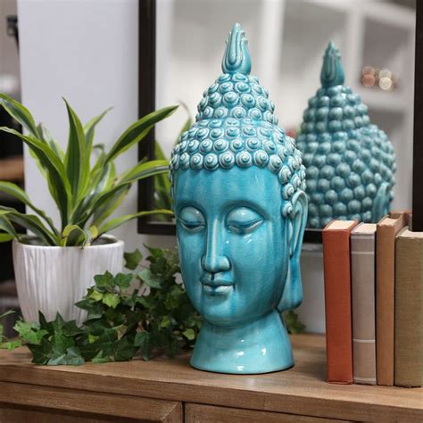 A Blue Buddha Statue Sitting On Top Of A Wooden Table Next To Books And