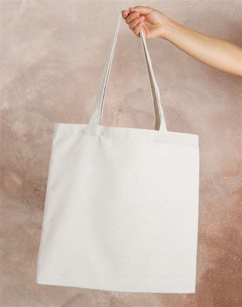 Mano femenina que sostiene la bolsa de asas contra fondo marrón Foto