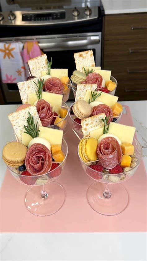 Two Wine Glasses Filled With Different Types Of Cheese And Crackers On