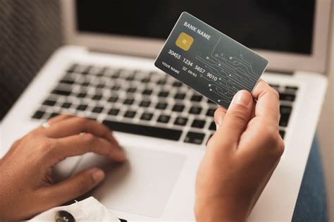 Mão segurando um cartão de crédito e trabalhando no laptop Foto Grátis