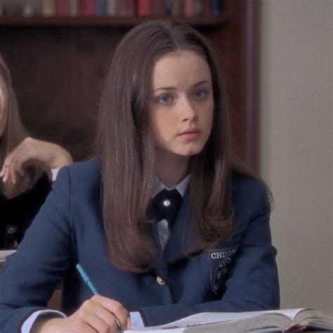 A Woman Sitting At A Desk With A Book In Front Of Her And Another