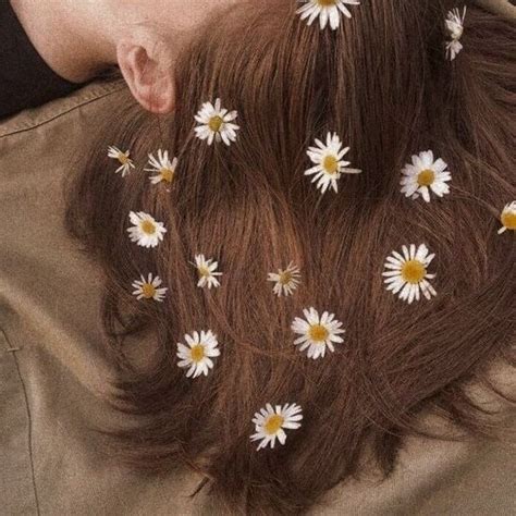 A Woman Laying Down With Daisies On Her Head And Hair In The Shape Of A