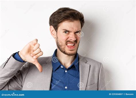 Close Up Of Disgusted Guy In Suit Grimacing Upset Showing Thumbs Down