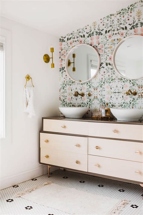 A Bathroom With Floral Wallpaper And Two Round Mirrors On The Wall